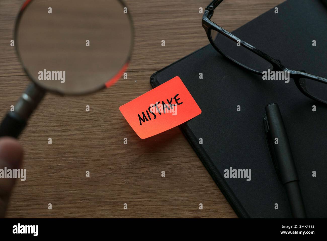 A hand holding a magnifying glass pointing over a book with a tag ...