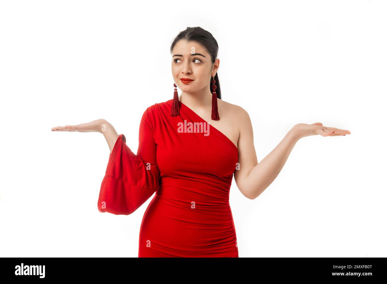 A questioned attractive female in red dress posing on white background ...