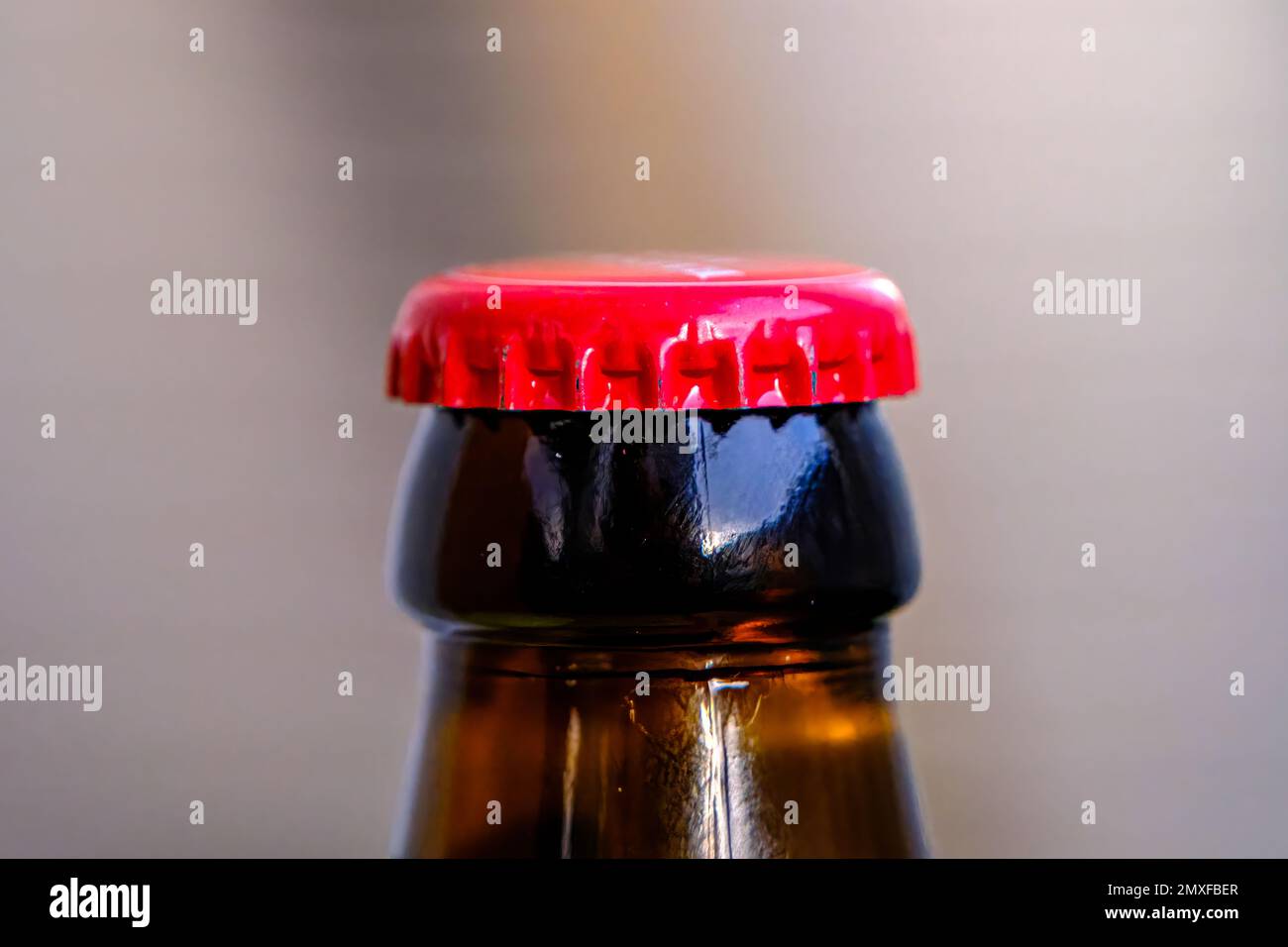 Brown glass beer bottle neck with red metal cap. close-up of unopened ...