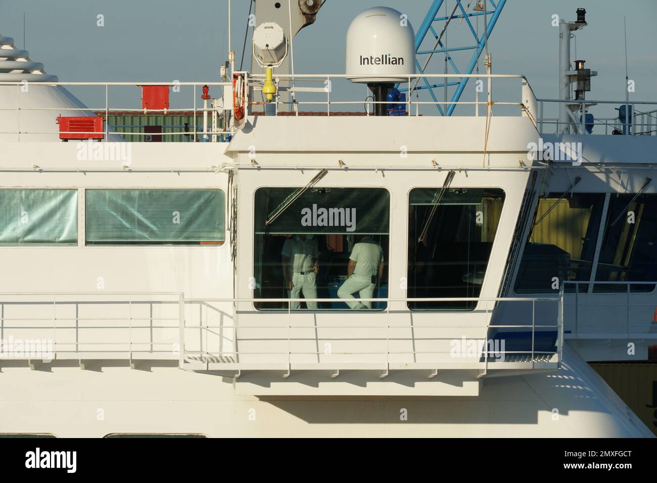 Two navigational officers in white uniforms observed through window of ...