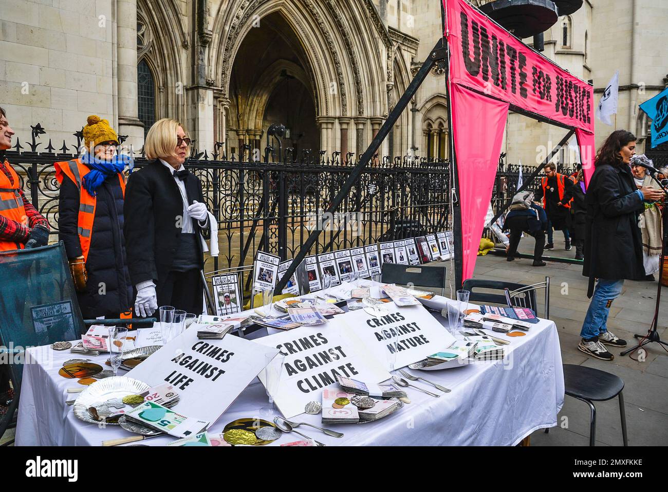 XR activist dressed up as waiter at the table covered with banknotes ...