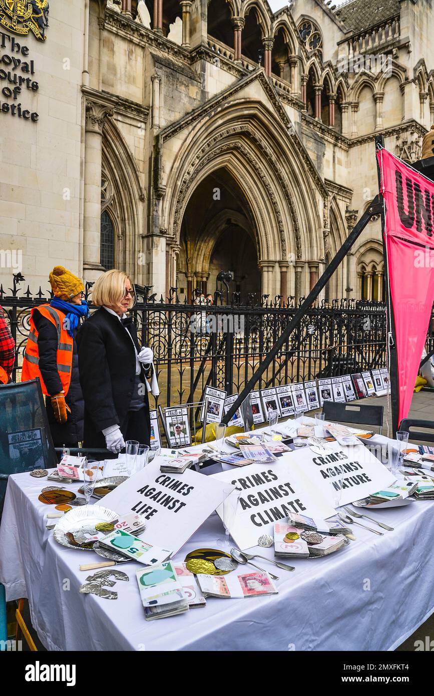 XR activist dressed up as waiter at the table covered with banknotes ...
