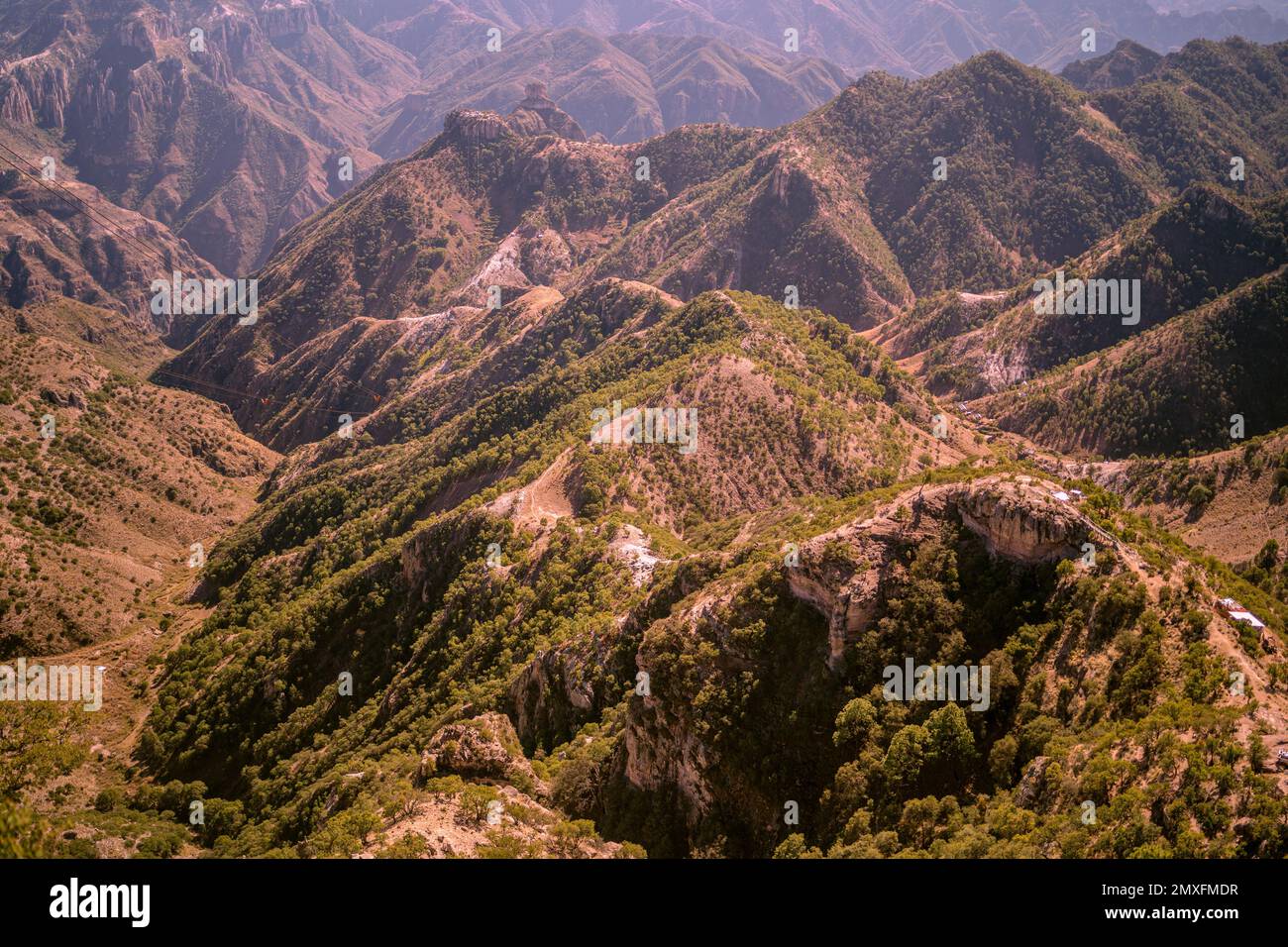 An aerial shot of Copper Canyon with rocky mountains and green trees ...