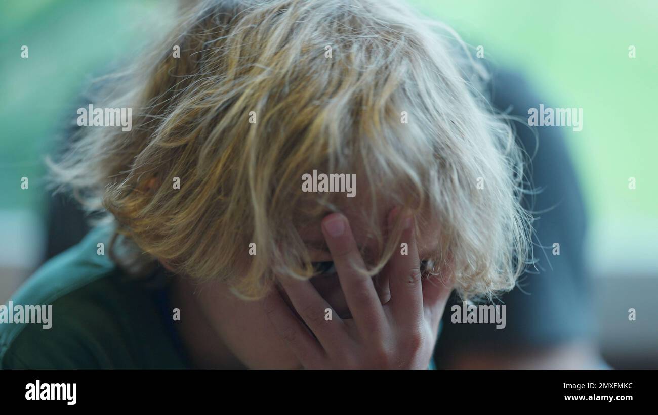 Child hiding face with hand feeling regret Stock Photo - Alamy