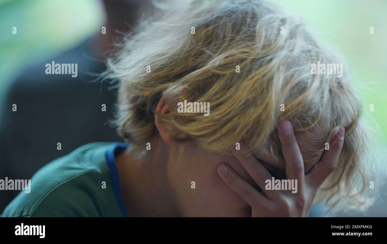 Child hiding face with hand feeling regret Stock Photo - Alamy