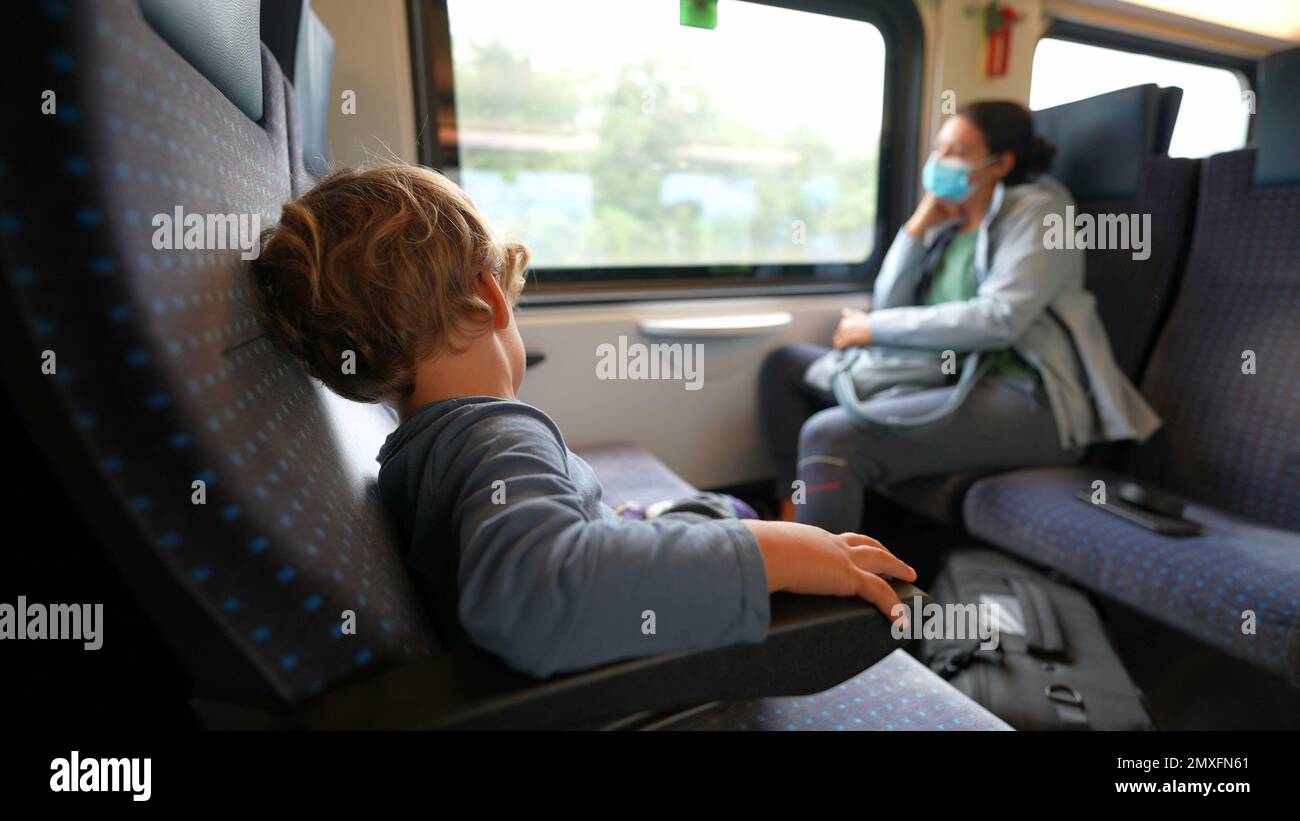 Child sitting on passenger seat inside train traveling on railroad ...