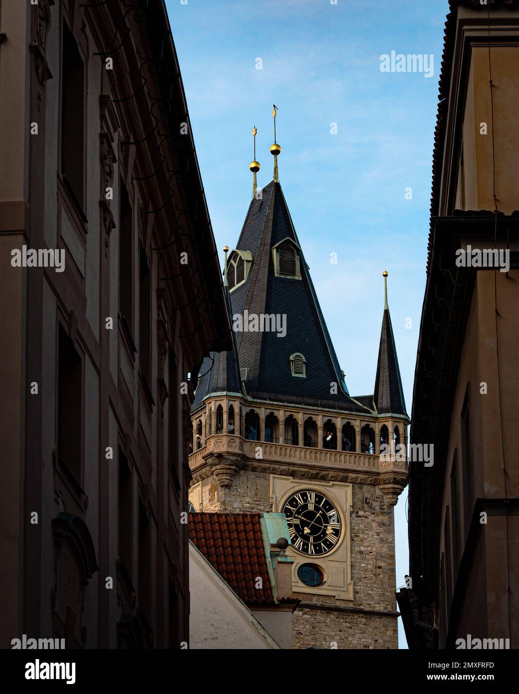 A vertical shot of the Astronomical Clock Tower seen through buildings ...