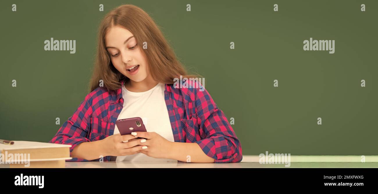 happy kid chatting on smartphone in classroom at blackboard, message ...