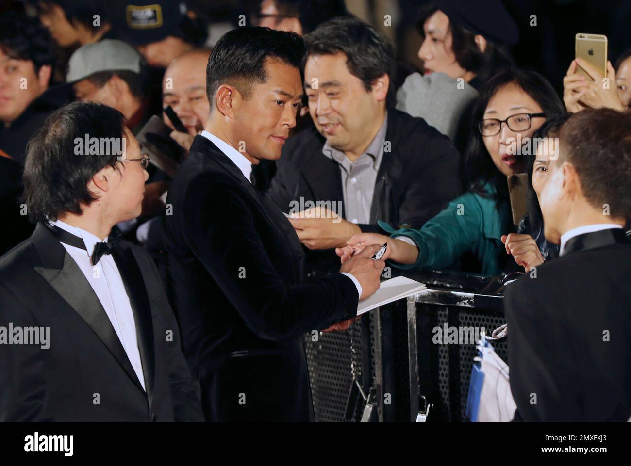 Hong Kong actor Louis Koo, center, gives his autograph to a fan on the ...