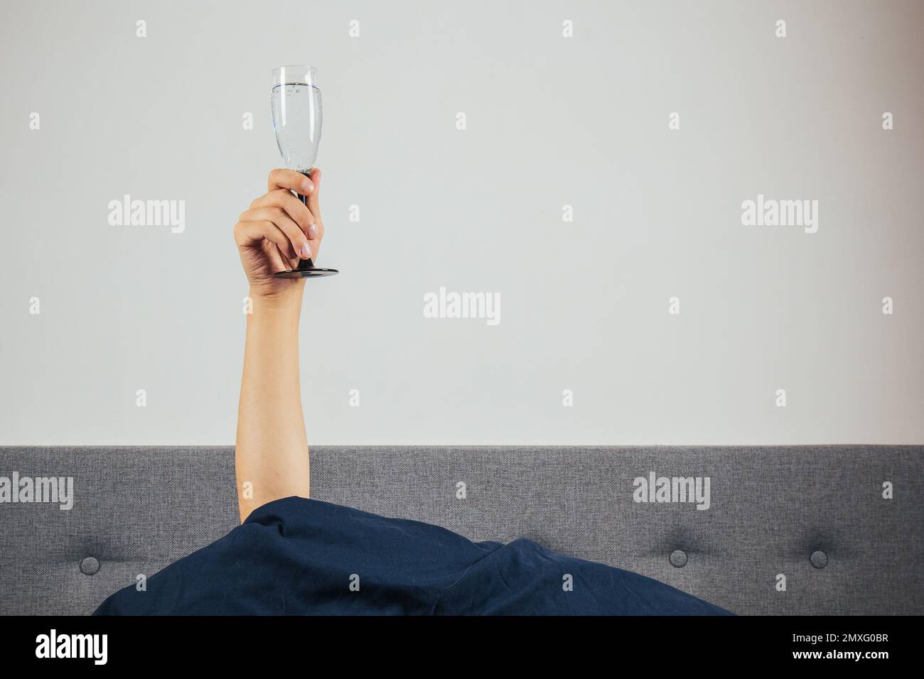 Champagne in a man's hand in bed. Hangover, alcohol intoxication ...
