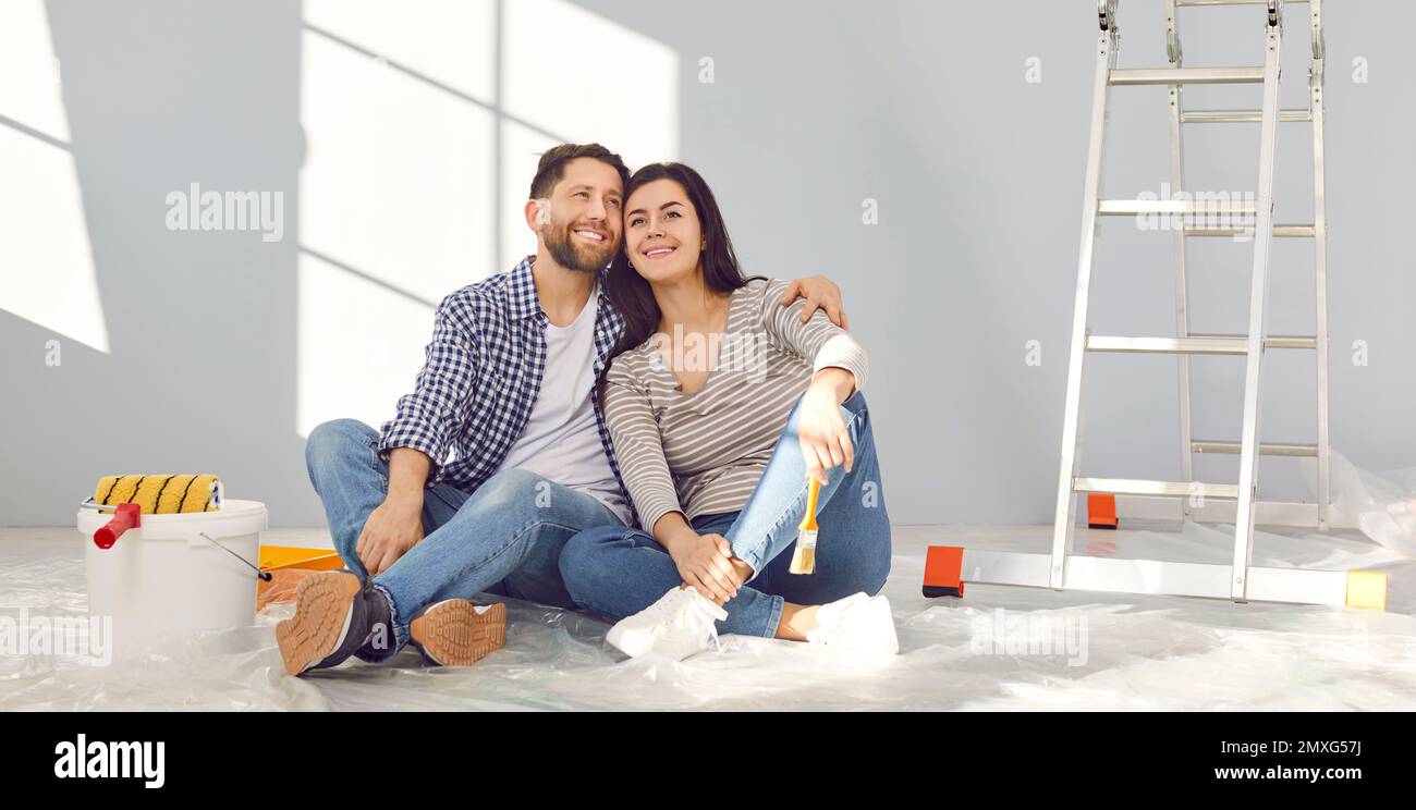 Happy young family couple relaxing on floor after doing renovations in ...