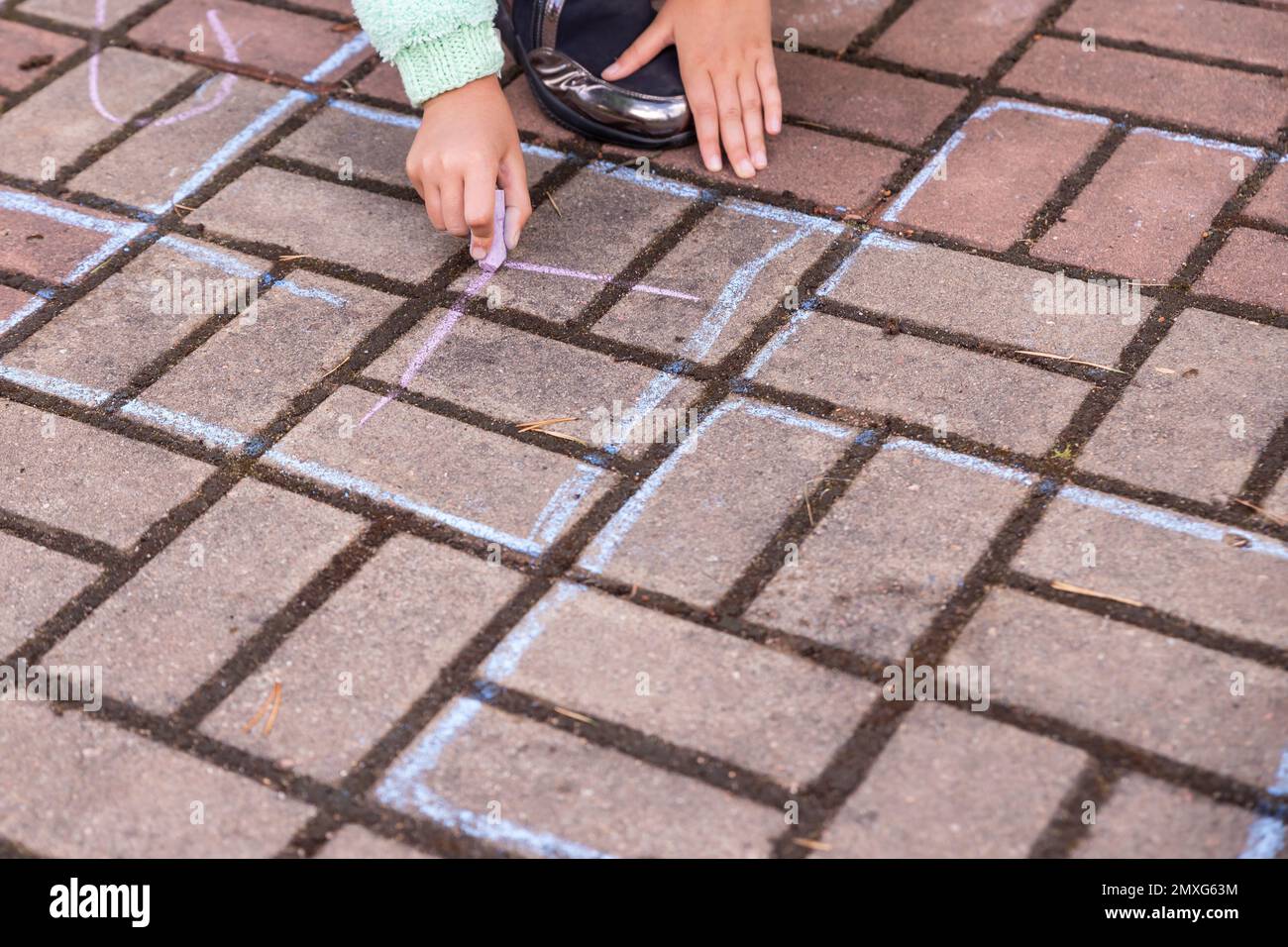 girl draws a hopscotch with chalk on the pavement.Child playing the ...