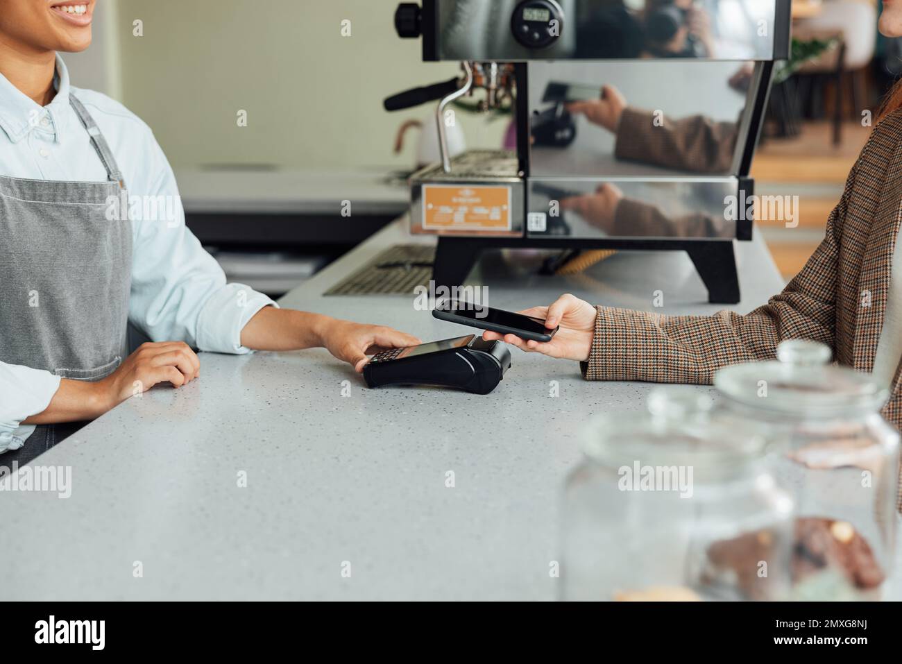 Side view of a barista at counter receiving payment from a customer in ...