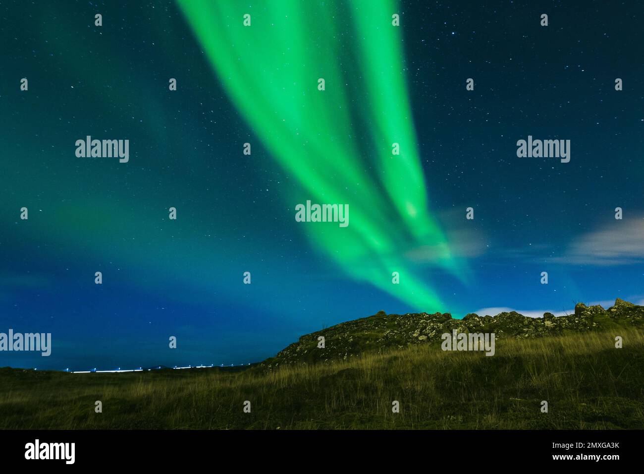 A landscape of a field with northern lights in the background at night ...