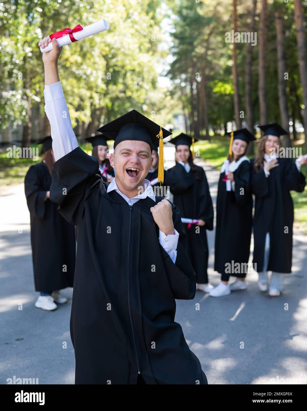 Happy young caucasian man celebrating graduation. Crowd of students ...