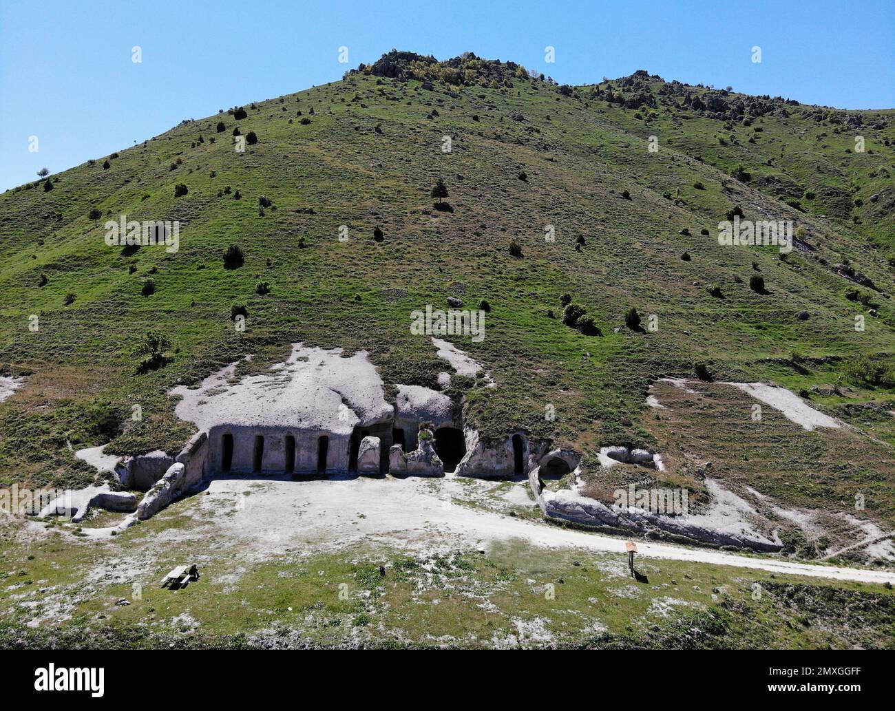 A high-angle view of stone caves at the Tepe Kermen under a hill in ...