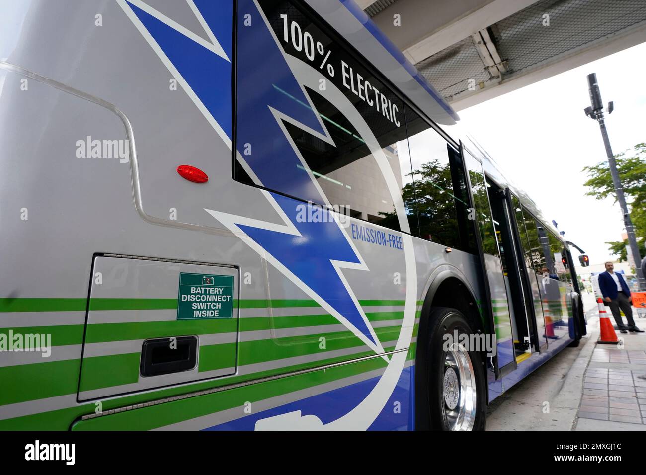 A new battery-powered bus, left, is shown parked at a bus stop ...