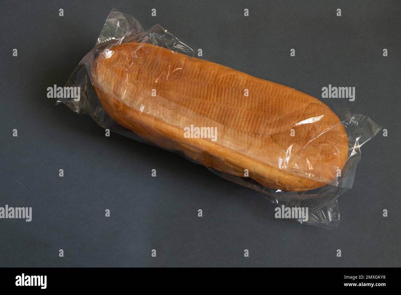 loaf of white bread in packaging on a dark isolated background close-up ...