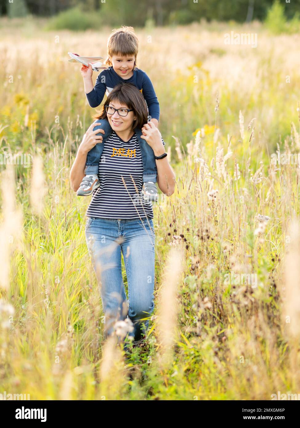Cute boy and his mother play with toy airplane. Happy kid dreams to be ...