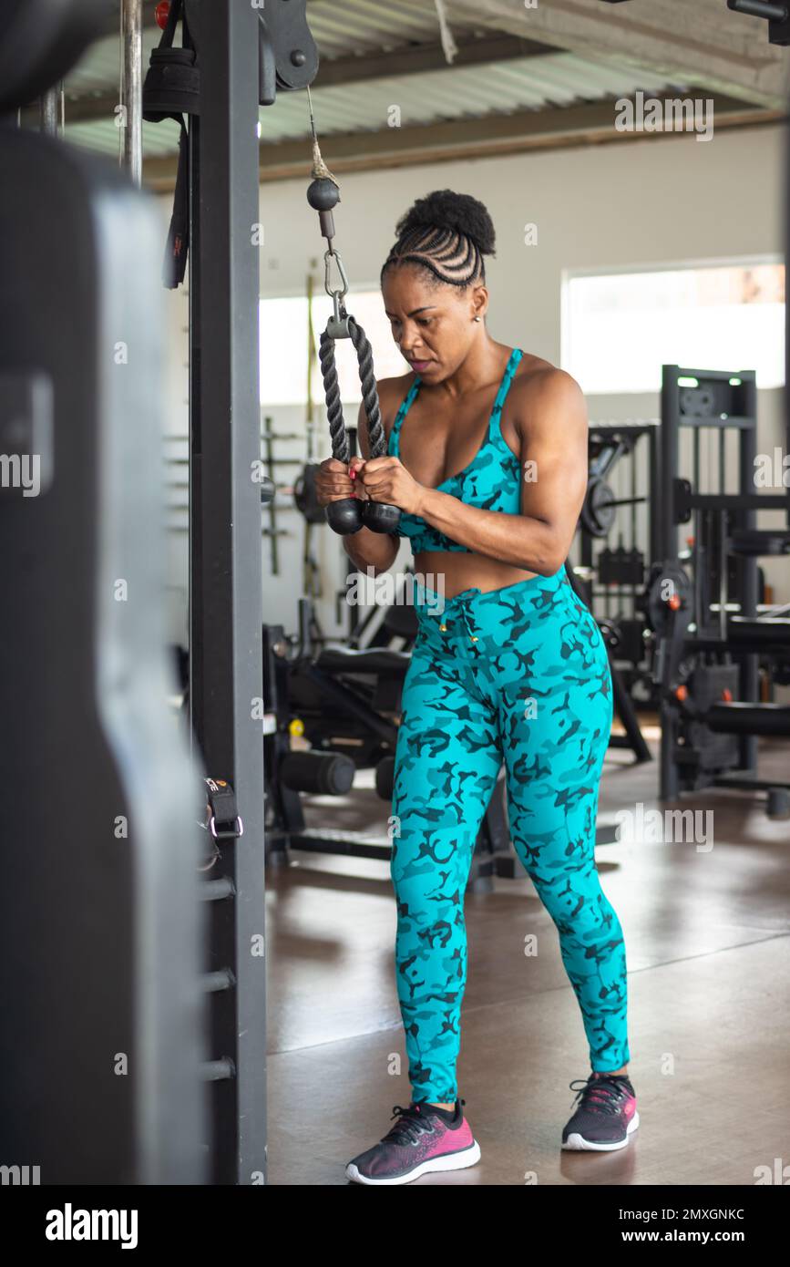 Sporty woman exercising pulley in studio. For arm and shoulder muscles ...