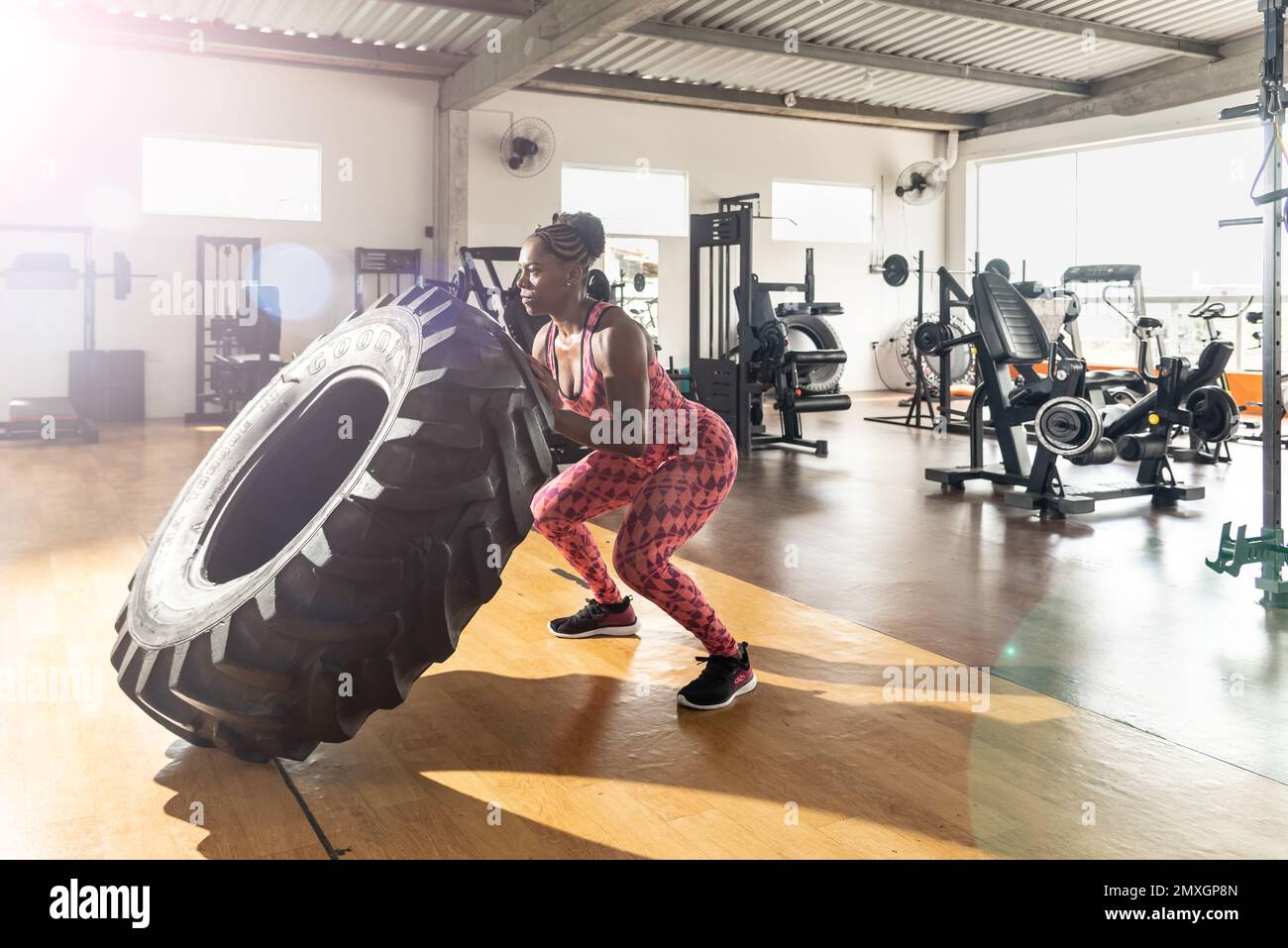Young strong woman lifting tire for strength training. Fitness exercise ...