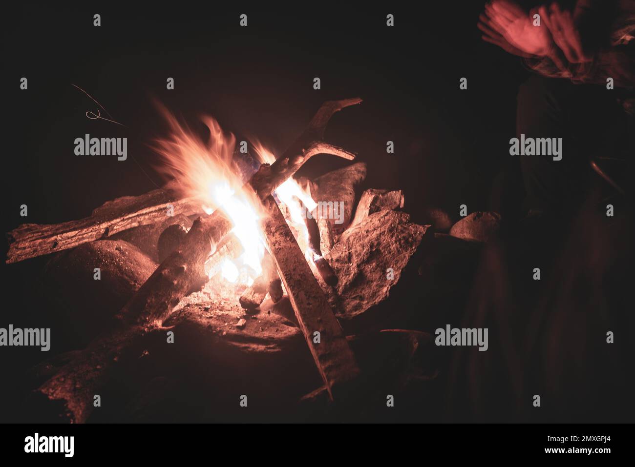 The girl's palms are warmed by the warm flame of a fire with firewood ...