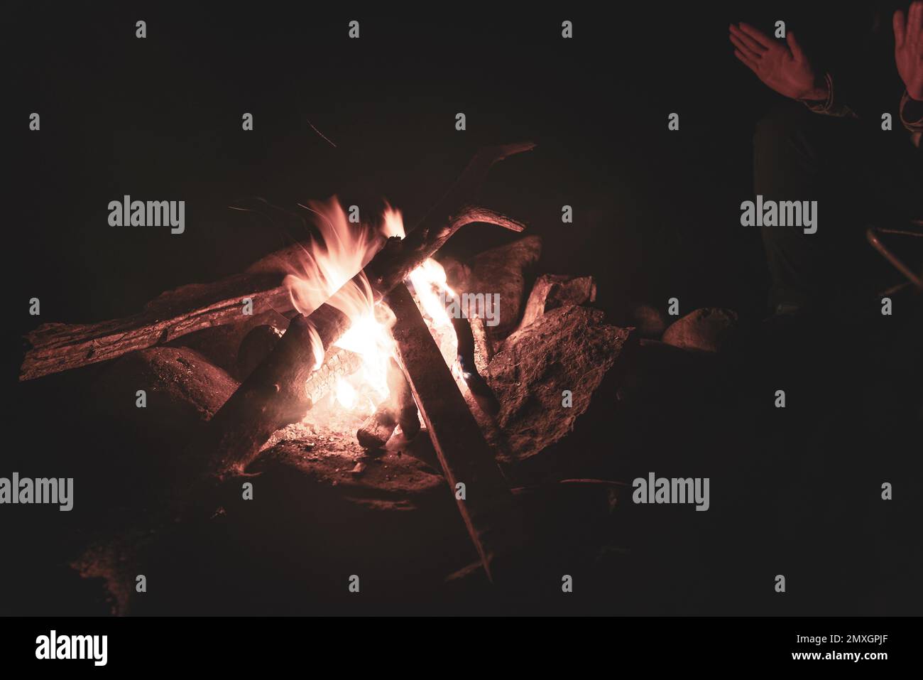 The girl's palms are warmed by the warm flame of a fire with sparks ...