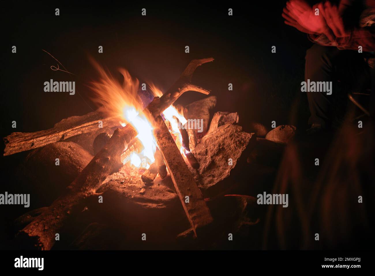 The girl's palms are warmed by the warm flame of a fire with firewood ...