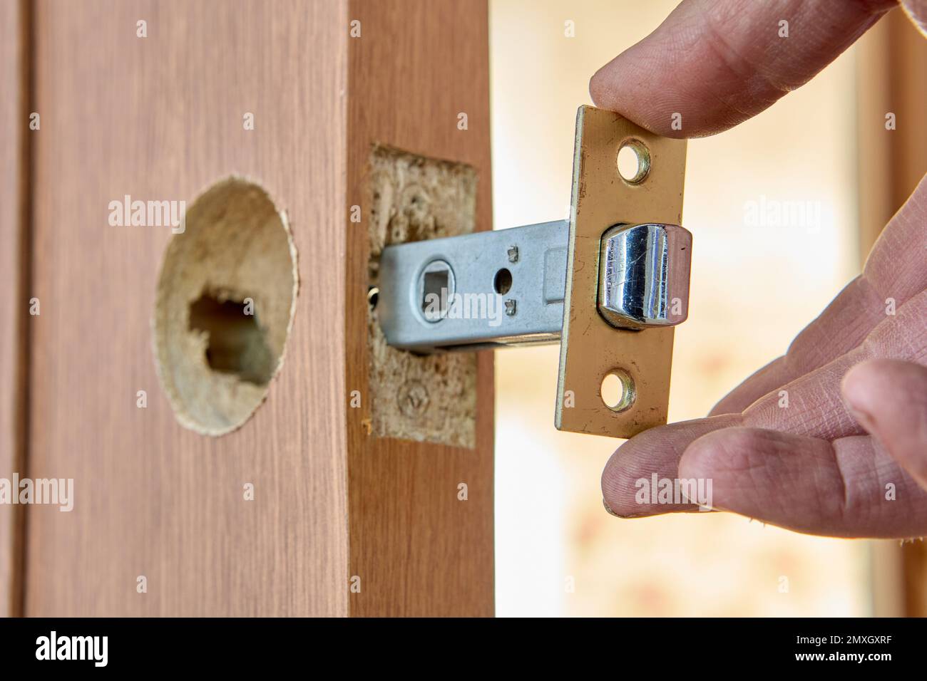 Installing door latch in slot of interior door Stock Photo - Alamy
