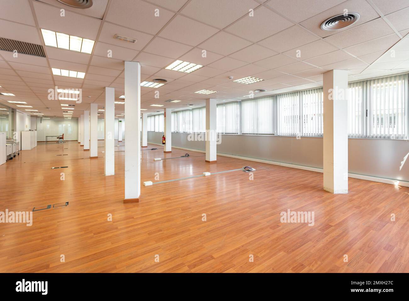 Large empty space with ceiling tiles, fluorescent lights, light brown ...
