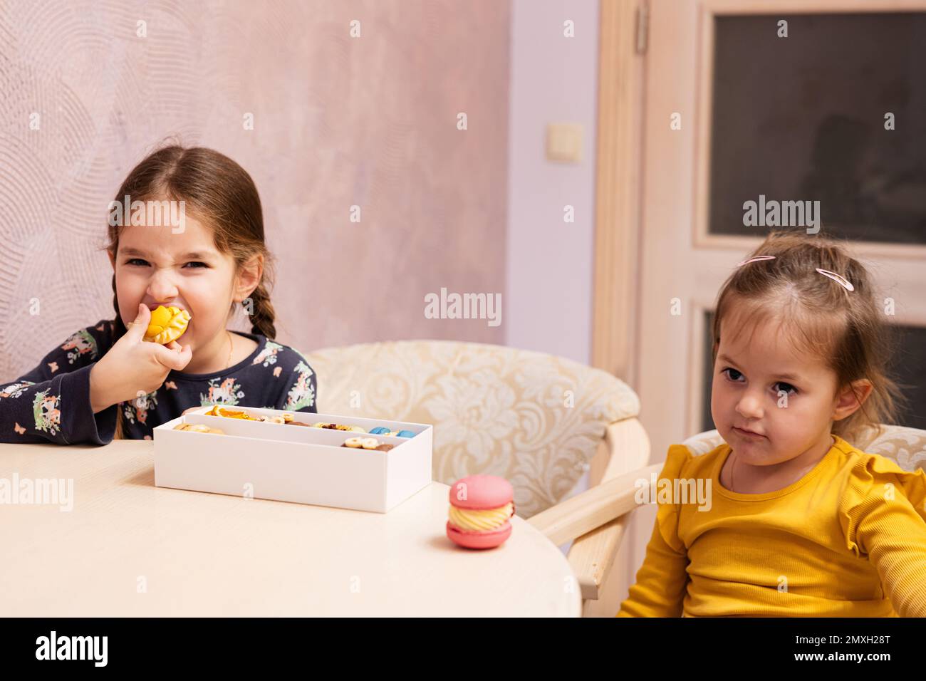 Two sister eat delicious tasty sweet color macarons Stock Photo - Alamy