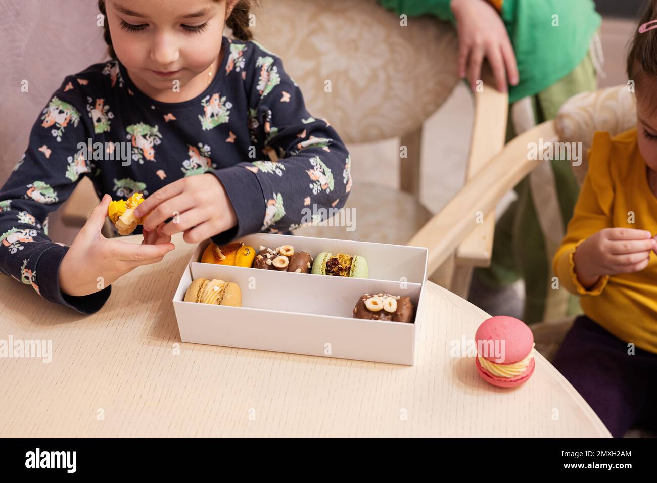 Three kids eat delicious tasty sweet color macarons Stock Photo - Alamy