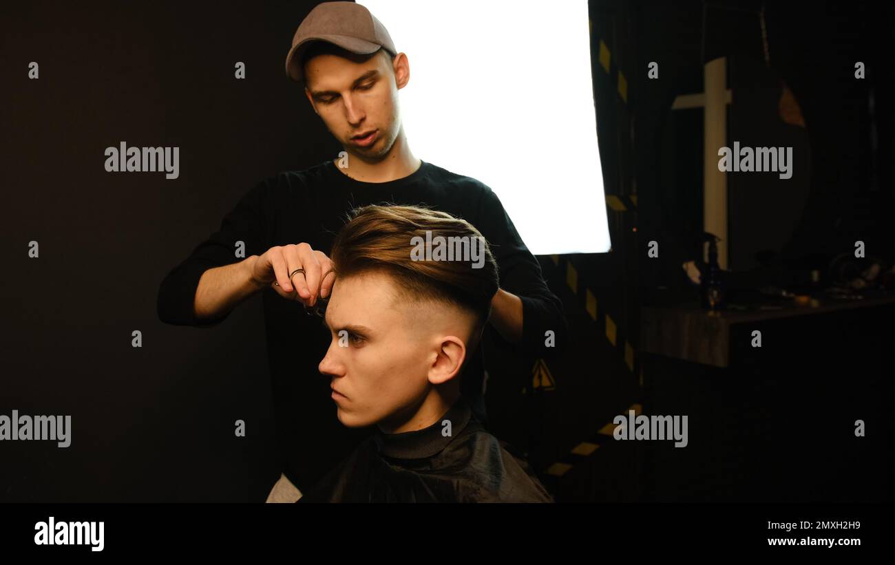Barber master hairdresser does hairstyle and style with scissors and ...