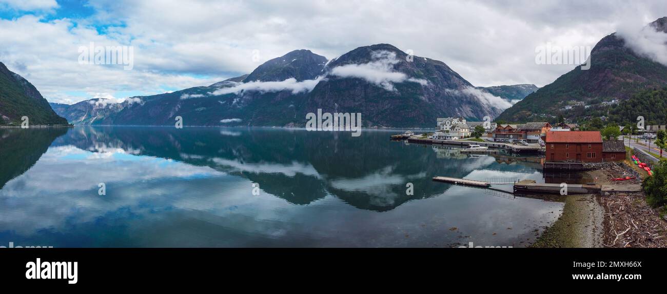 A panoramic shot of the beautiful nature scene with houses and a lake ...