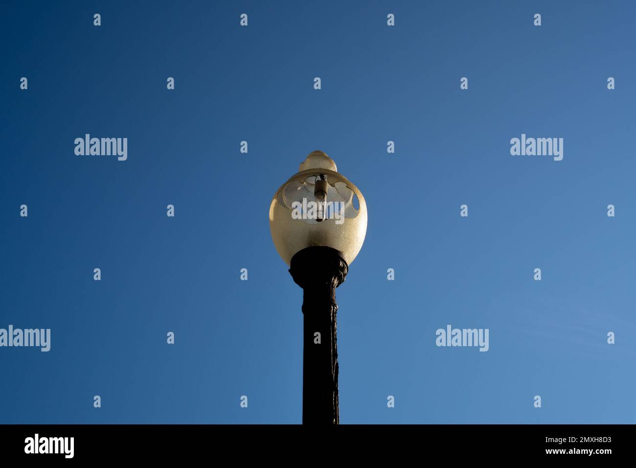 A low angle shot of a metal pole with a broken light under a blue sky ...