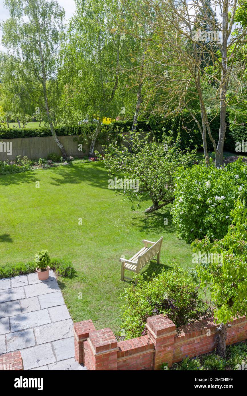 Wooden garden bench on lawn in a large luxury UK garden in spring Stock ...