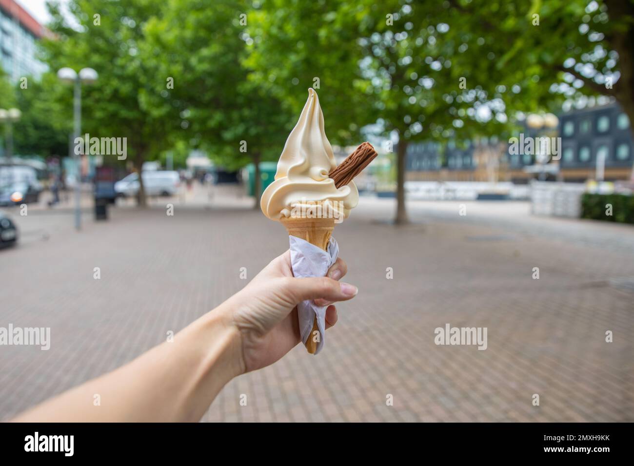 A hand holding a delicious ice cream cone in a city square Stock Photo ...