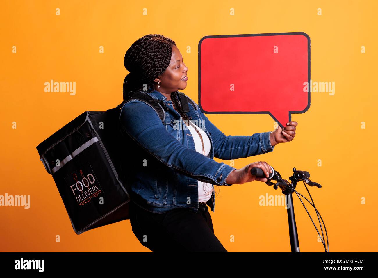 Deliverywoman carrying takeaway thermal backpack while riding bike ...