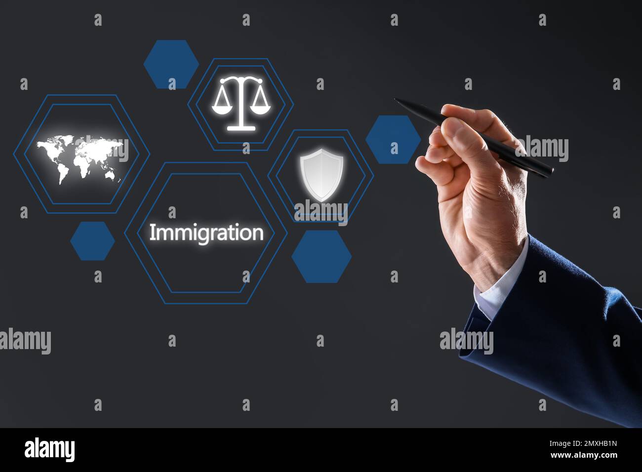 Man pointing at icons on virtual screen with pen against dark grey ...