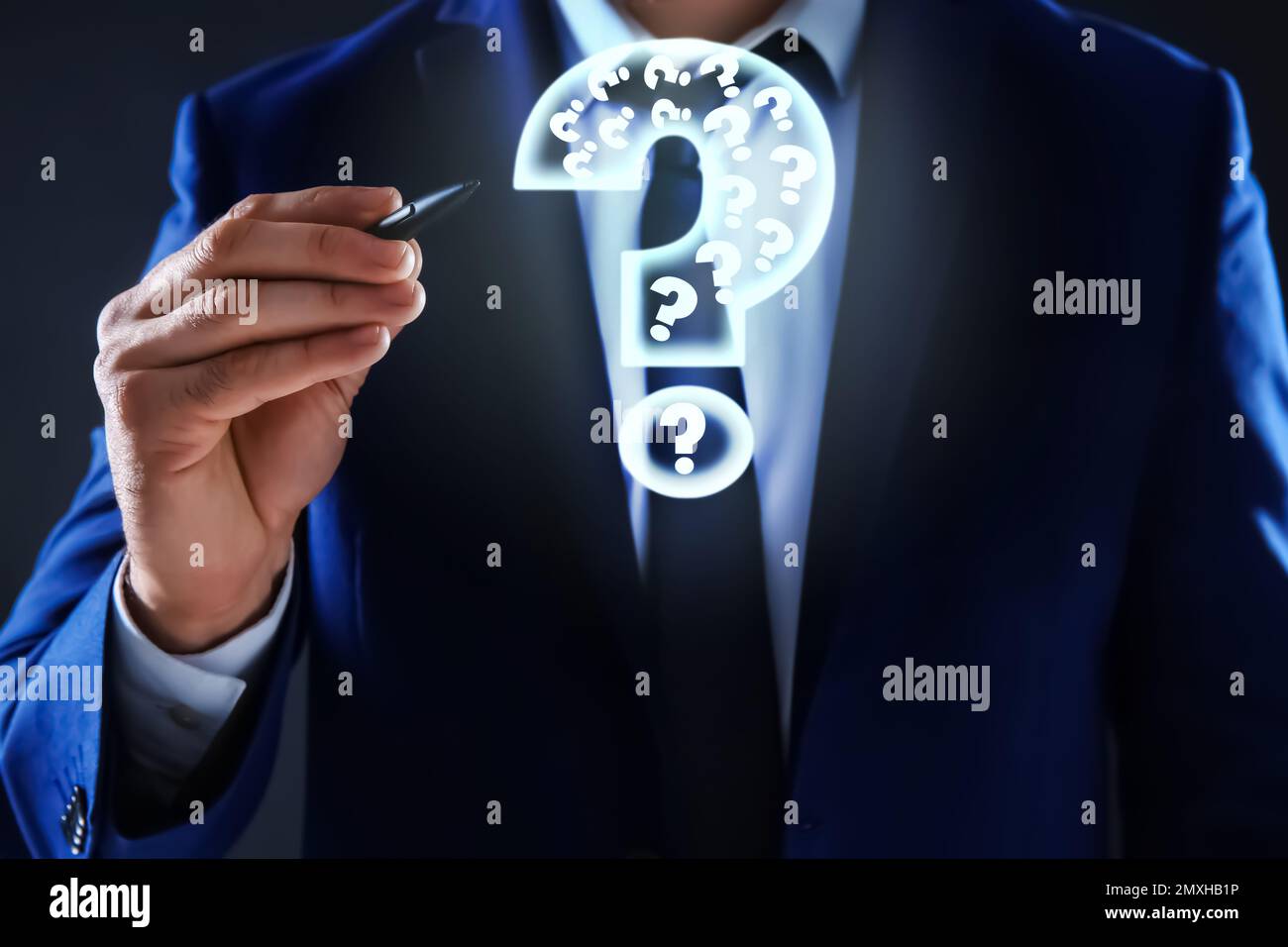 Businessman using virtual screen with question mark symbol on dark ...