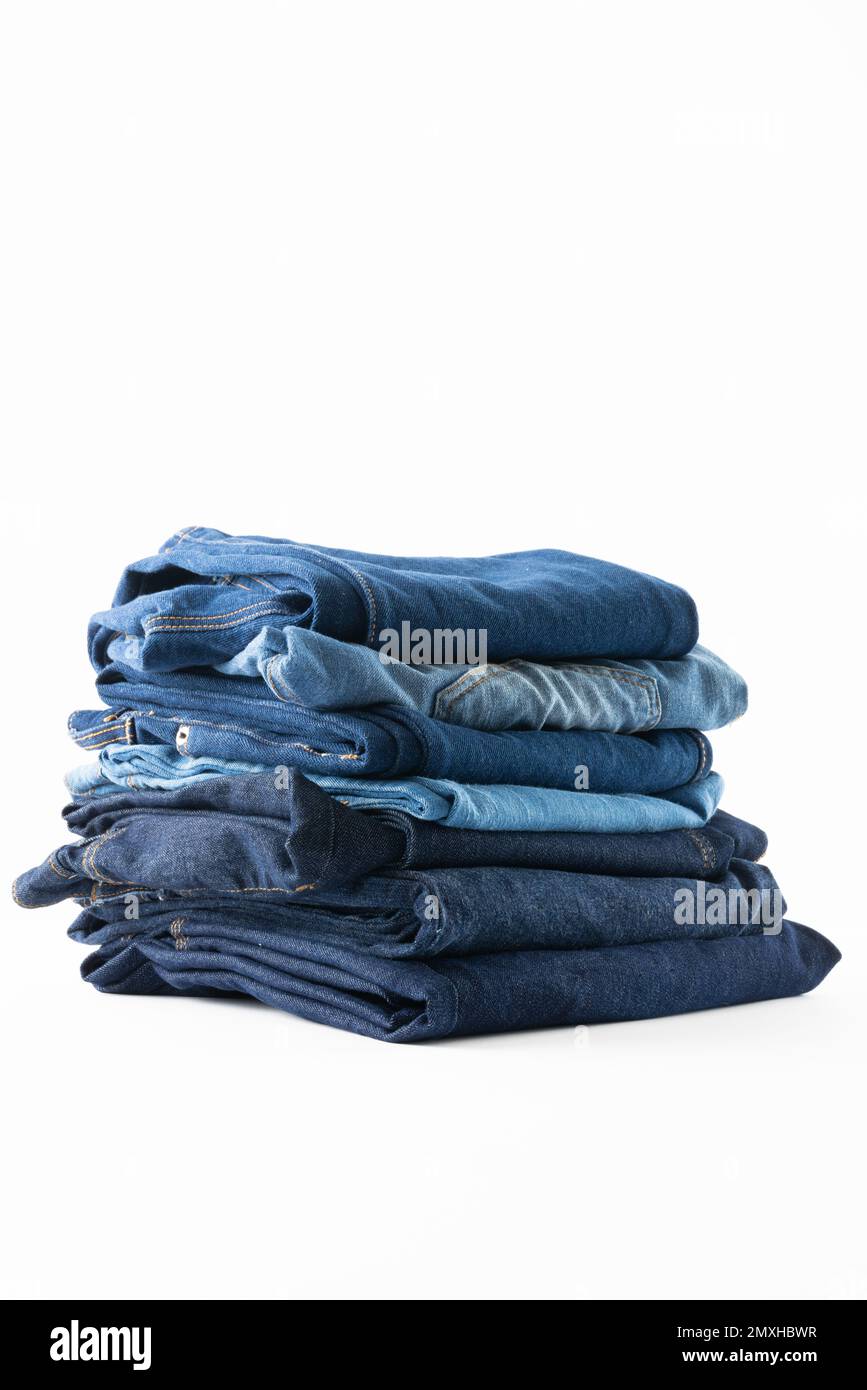 Vertical image of diverse folded jeans lying in stack on white ...