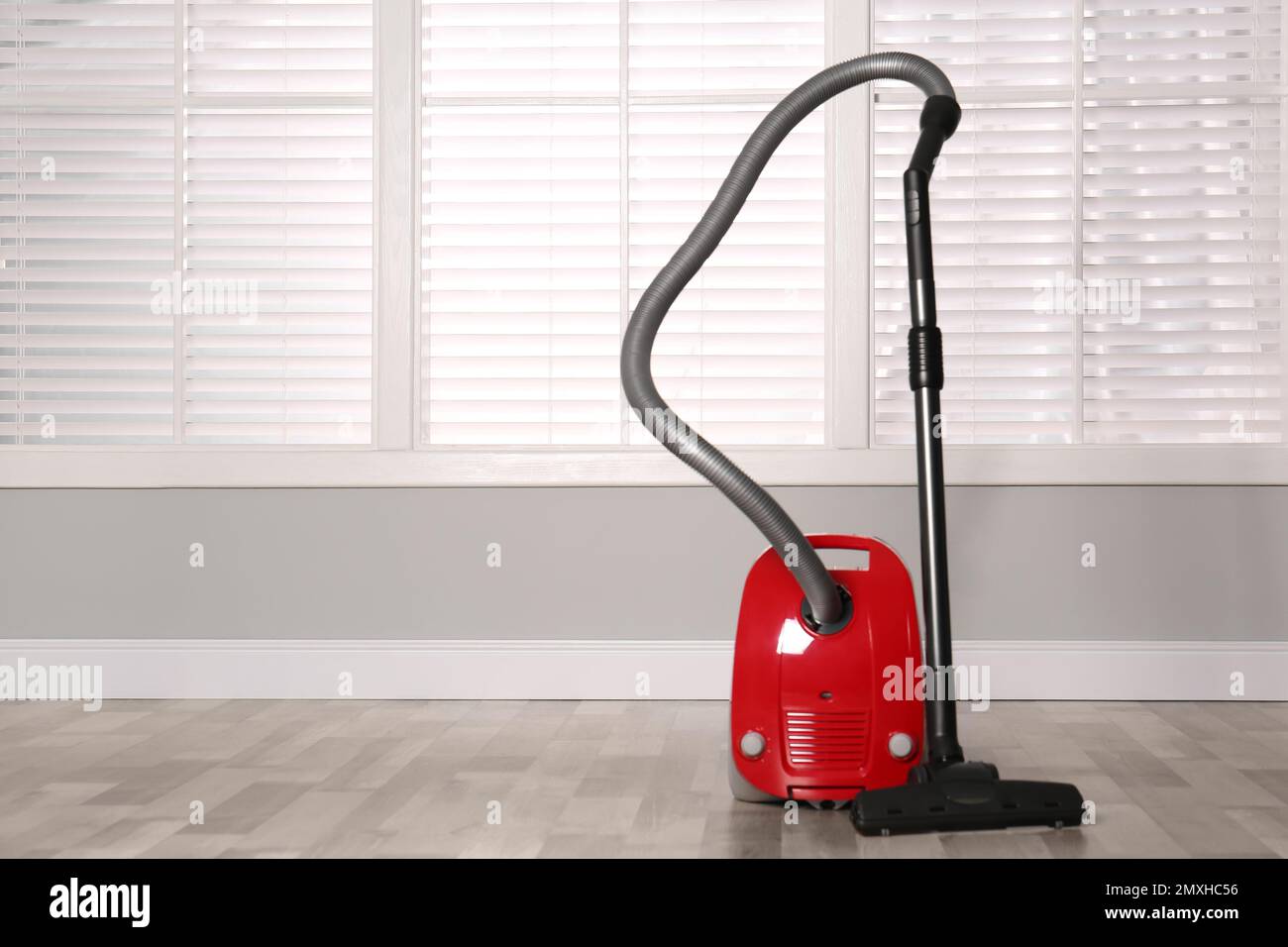 Modern red vacuum cleaner on floor indoors, space for text Stock Photo ...