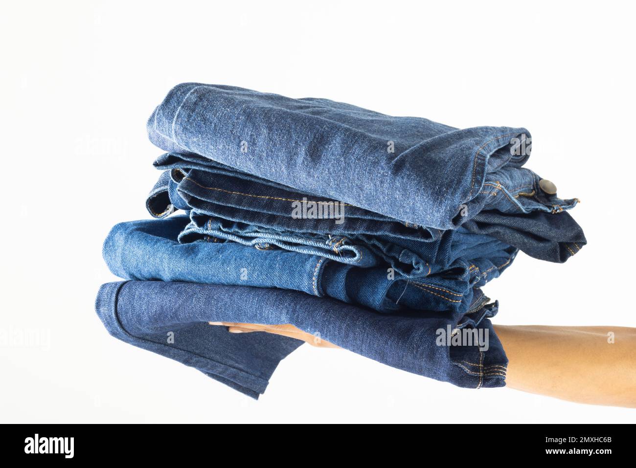 Diverse folded jeans in stack on hands of caucasian woman over white ...