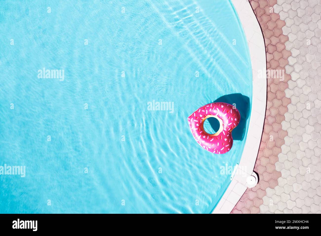 Heart shaped inflatable ring floating in swimming pool, top view with ...