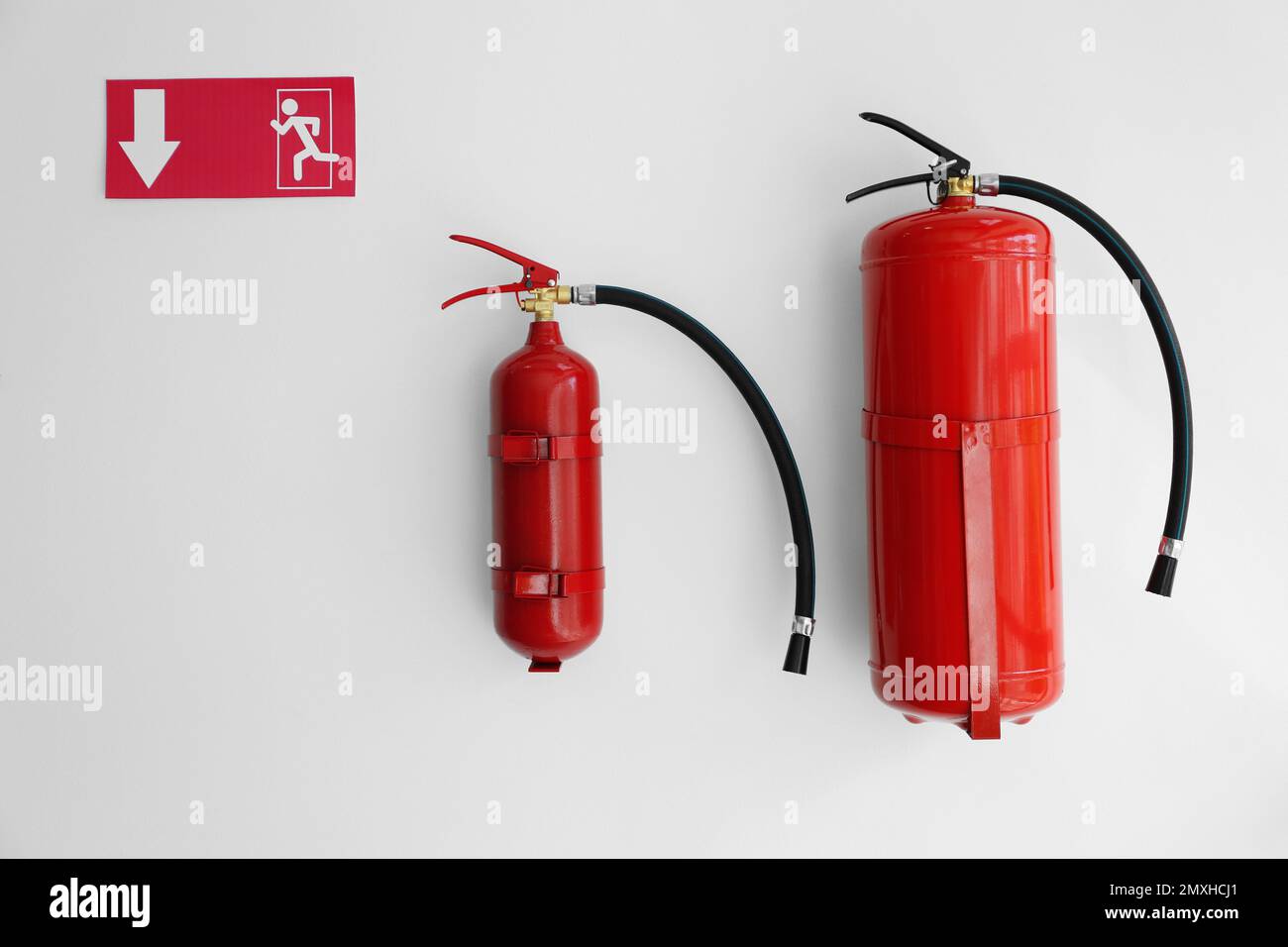Fire extinguishers and emergency exit sign on white wall Stock Photo ...