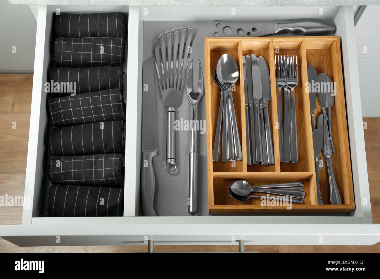 Open drawer with different utensils and folded towels, top view. Order ...