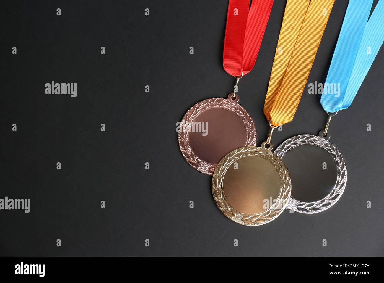Gold, silver and bronze medals on black background, flat lay. Space for ...