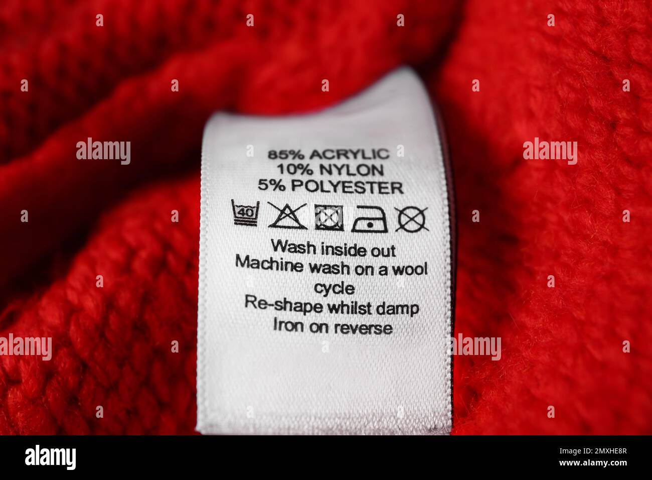 Clothing label with care symbols and material content on red sweater ...