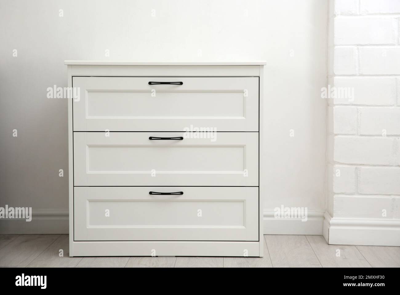 Modern white chest of drawers near light wall in room. Interior design ...