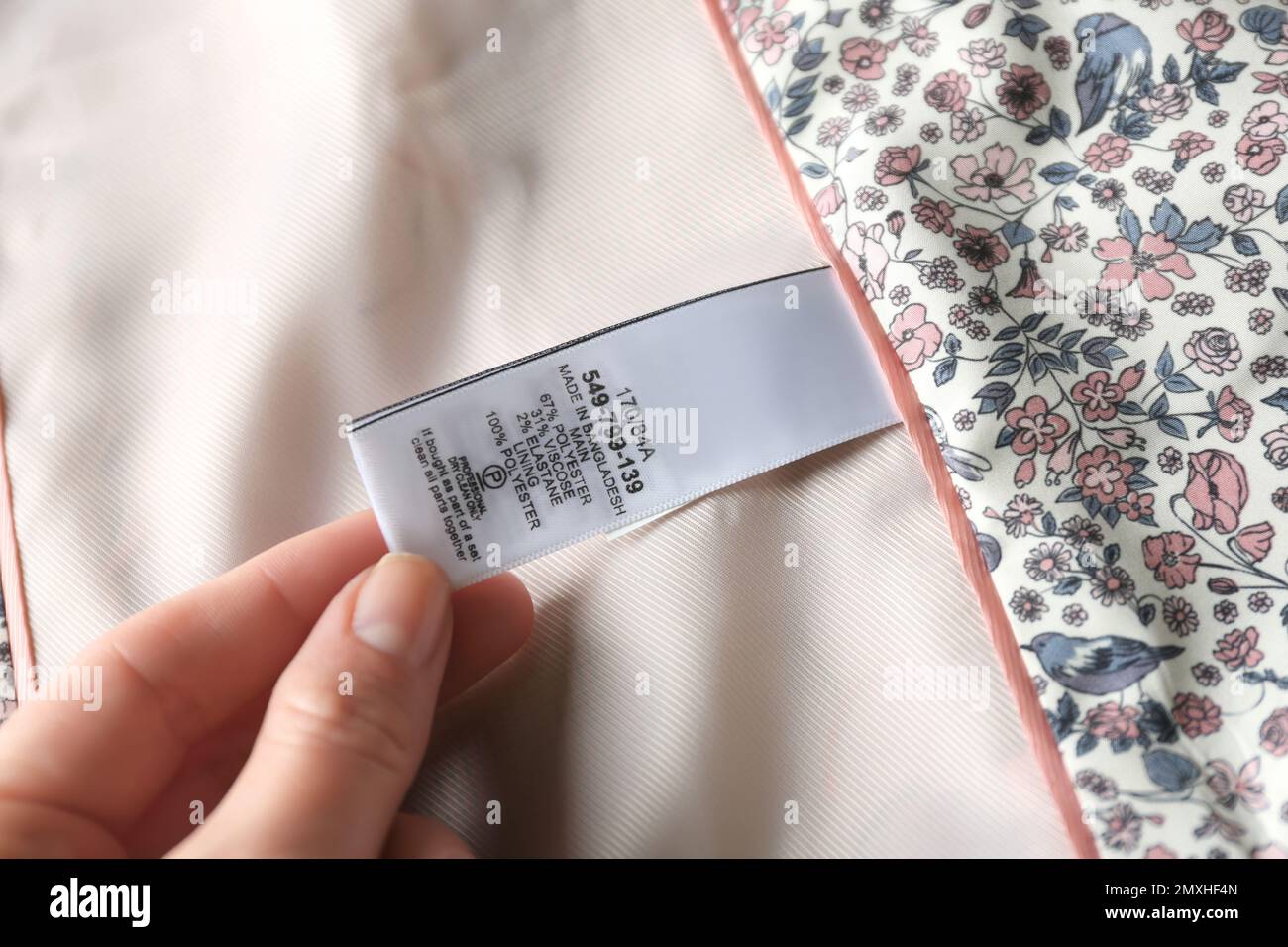 Woman reading clothing label with size and content information on light ...